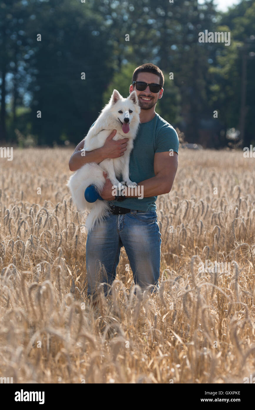 Young Man Standing With Dog German Spitz In Harvested Field Stock Photo ...