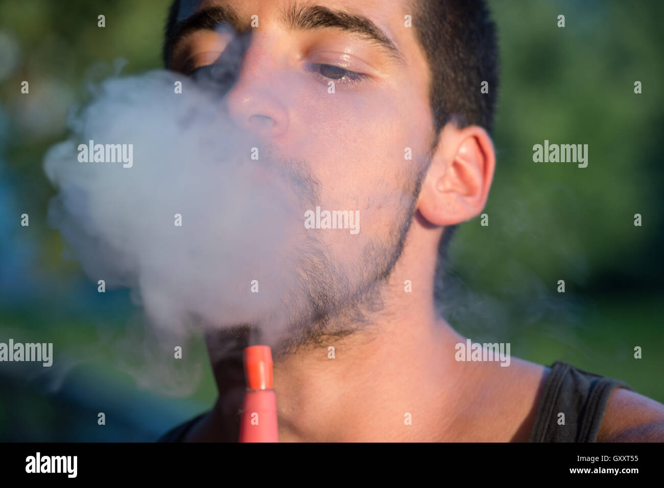 Young Man Smoking Shisha Outdoors - Man Exhaling Smoke Inhaling From A ...