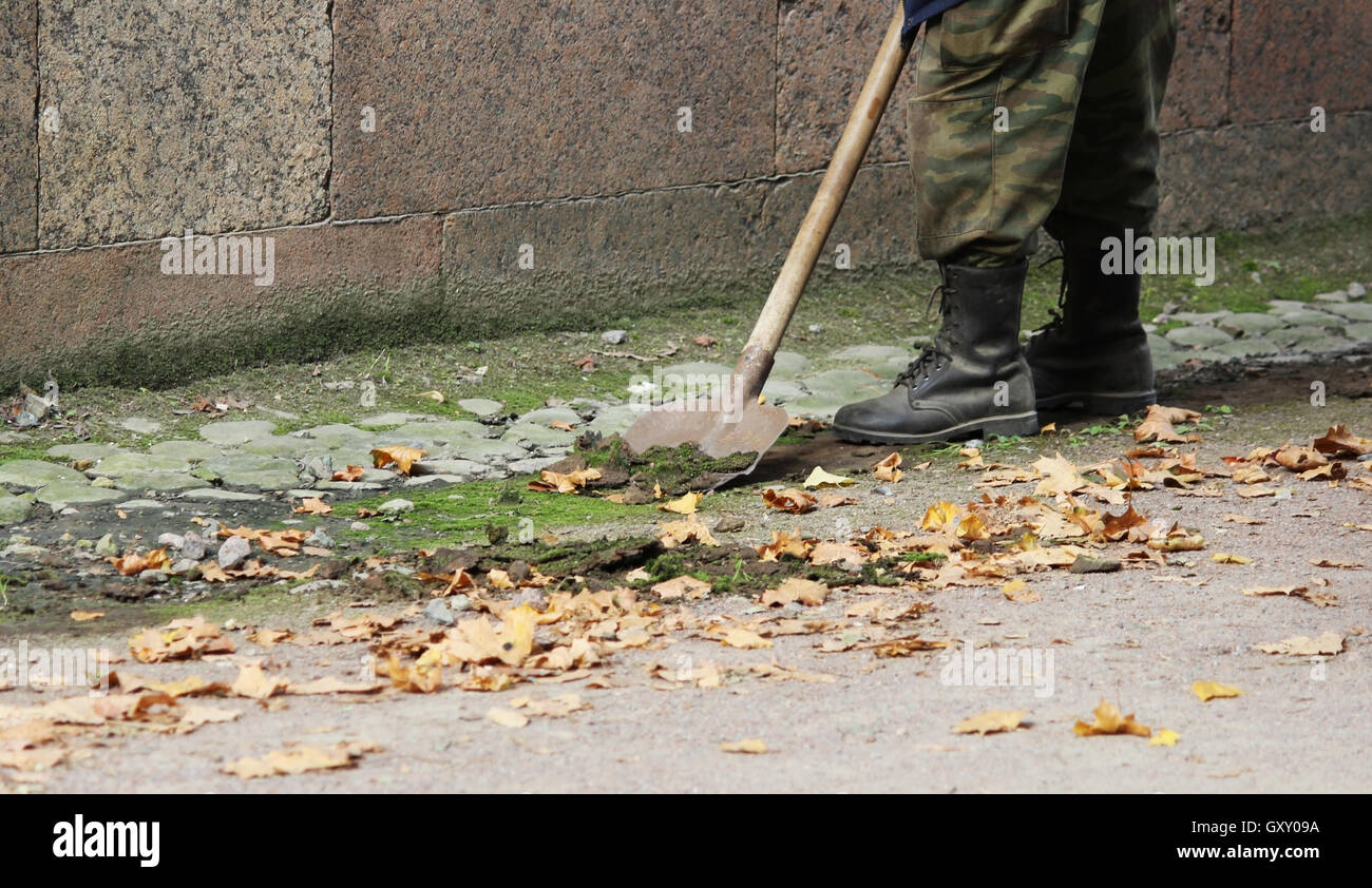 working man cleans a ditch with a shovel of soil and sand near the ...