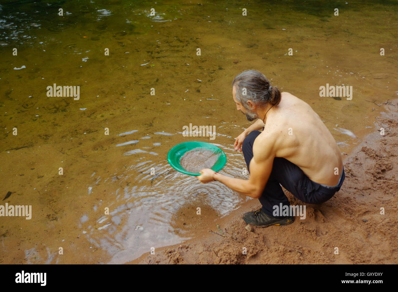 a man gold panning in a river with a sluice box Stock Photo - Alamy