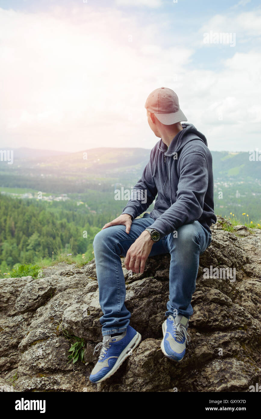 Male backpacker resting and enjoying the mountain sitting on rock in ...