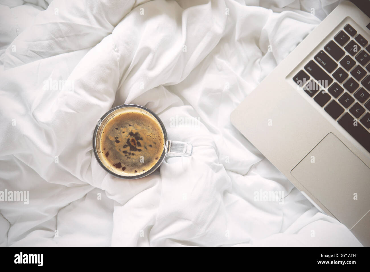 Working in bed , laptop and cup of coffee on white bed, morning light ...