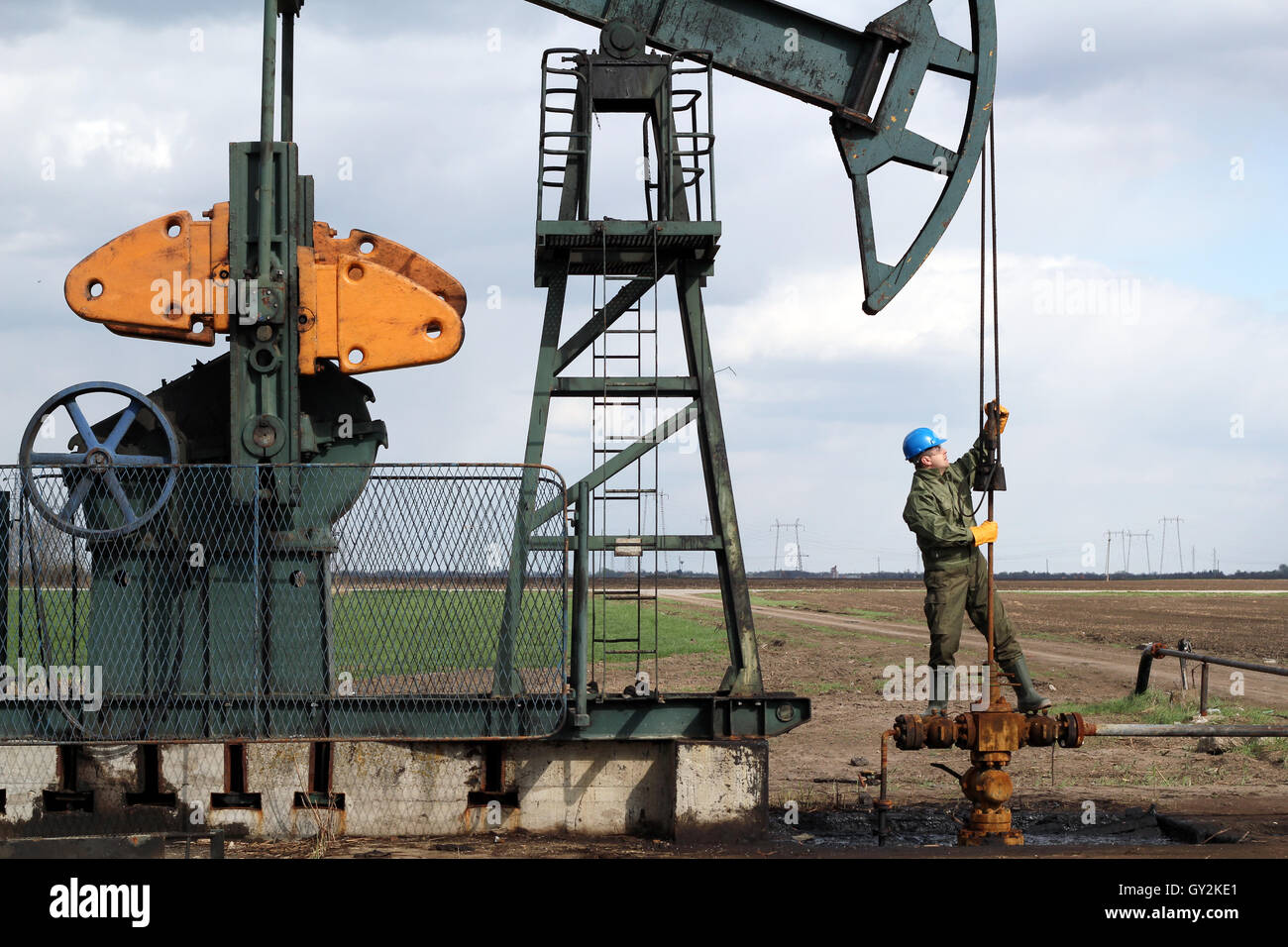 oil worker standing at pipeline and check pump jack Stock Photo - Alamy