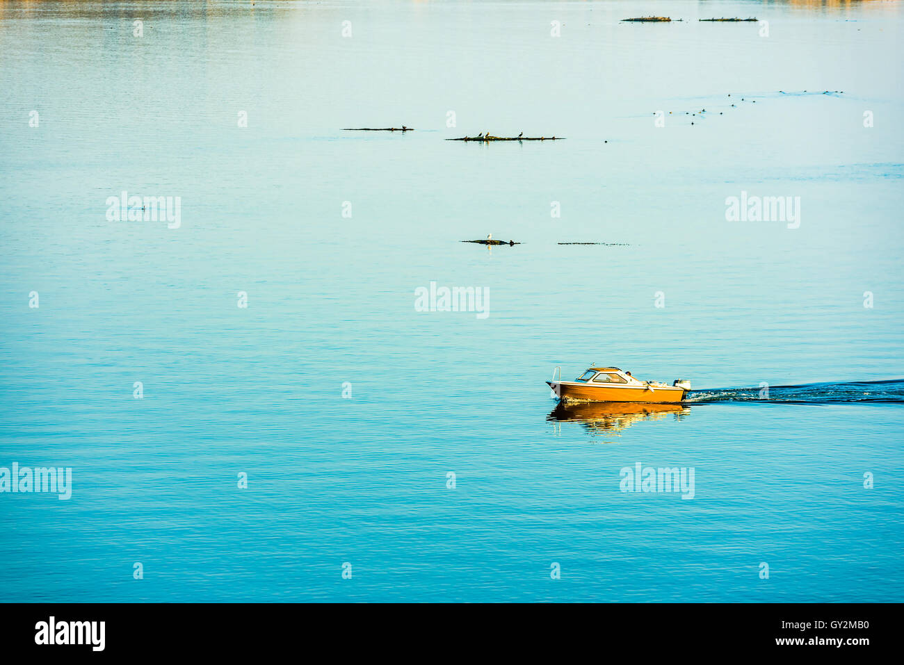 Small motorboat moving slowly through windless sea in the archipelago ...