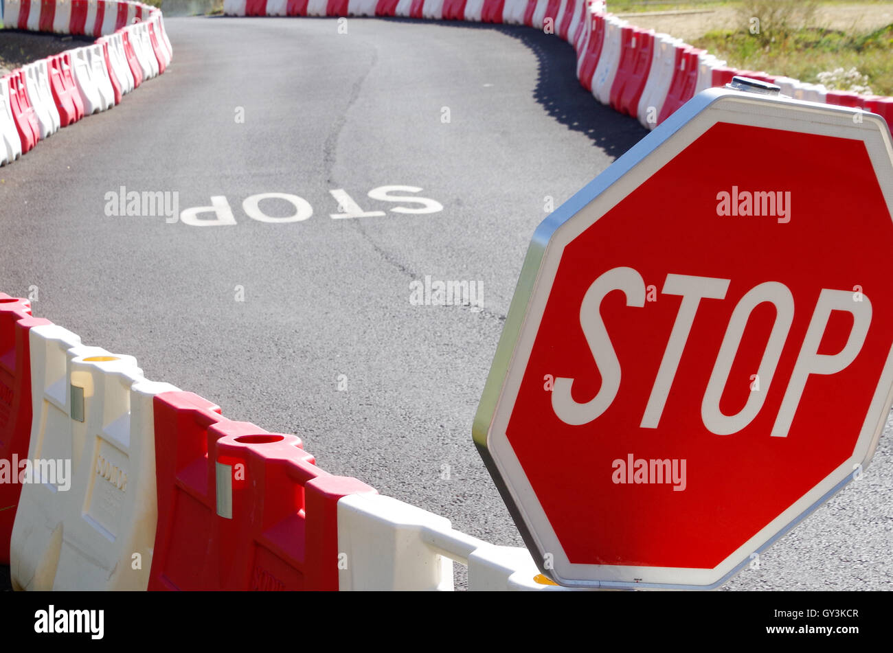 Red stop sign and STOP written on aslphalt at a junction under ...
