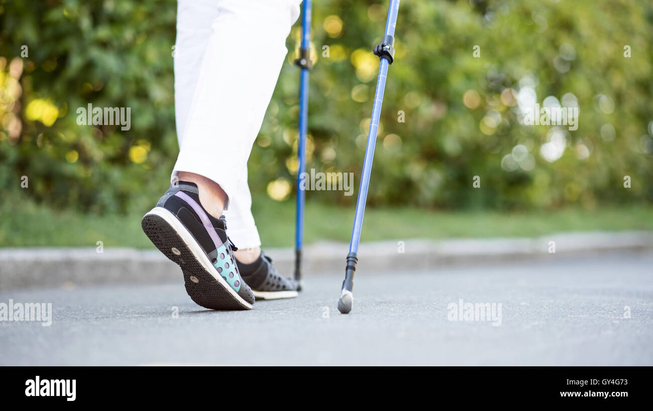 Female in black shoes walking with tracking sticks Stock Photo - Alamy