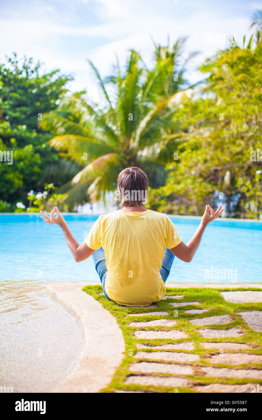 Young man sitting in lotus position near the pool Stock Photo - Alamy