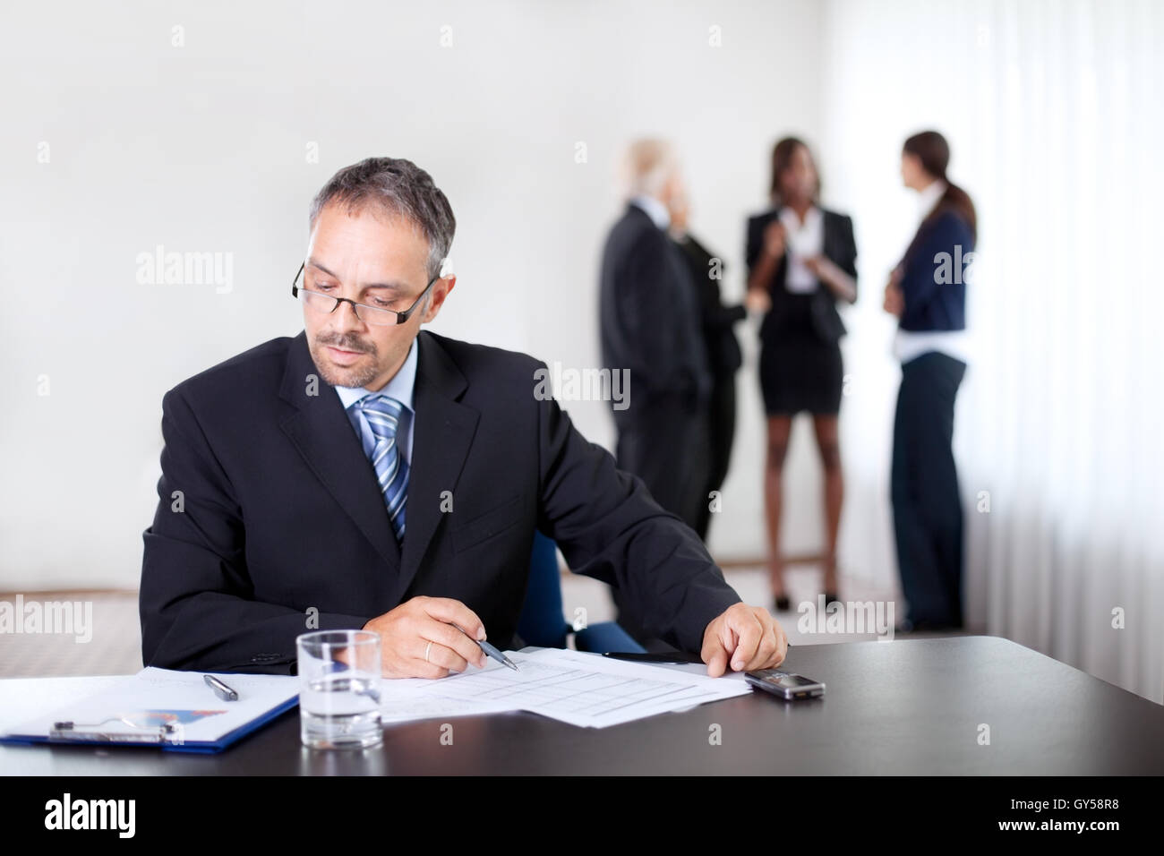 Confident businessman reading and writing Stock Photo - Alamy