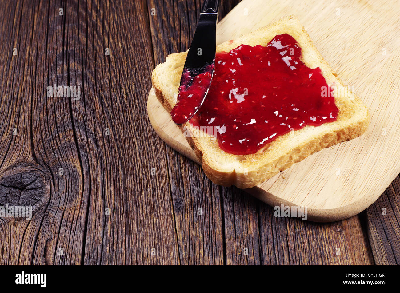 Toasted bread with raspberry jam on cutting board Stock Photo - Alamy
