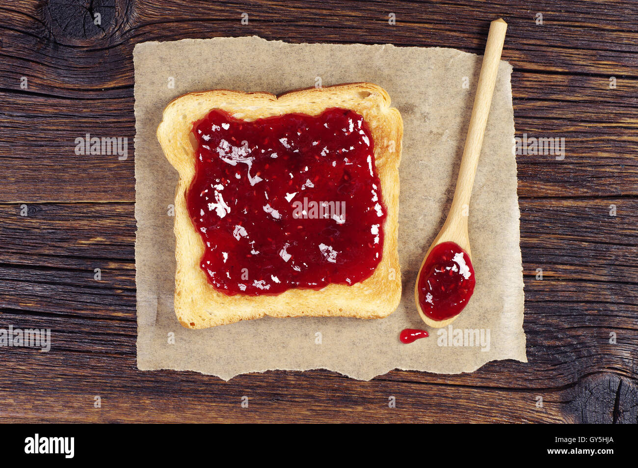 Toast with raspberry jam and spoon on dark wooden table. Top view Stock ...