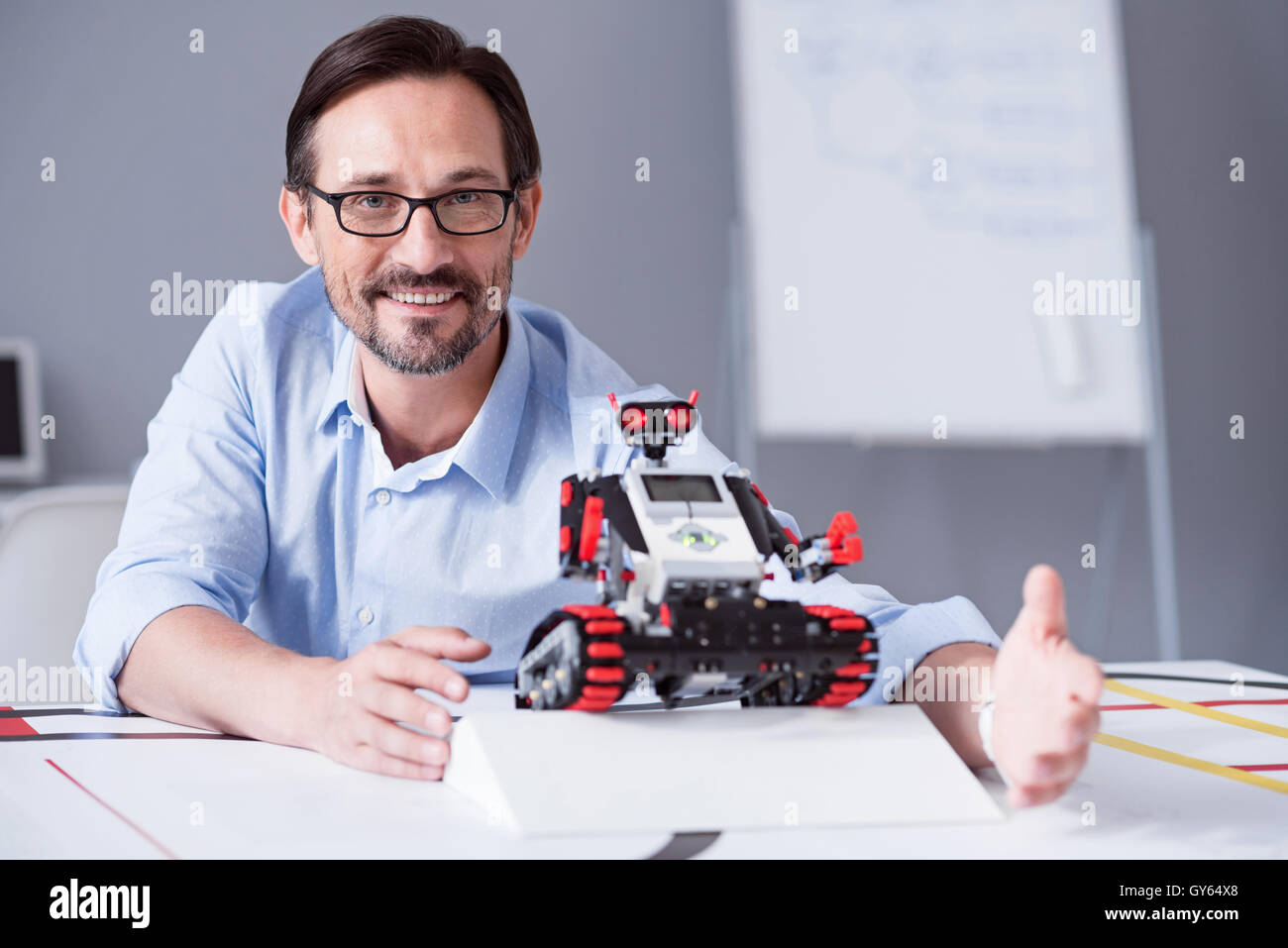 Handsome man posing with a small red robot Stock Photo - Alamy