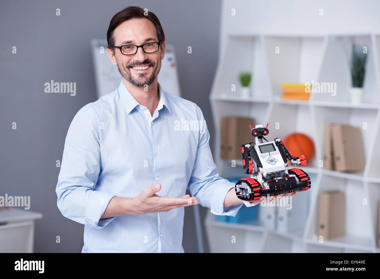 Smily and attractive presenter demonstrating little robot Stock Photo ...