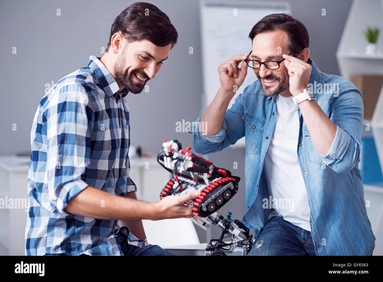 Cheerful colleagues testing robot Stock Photo - Alamy