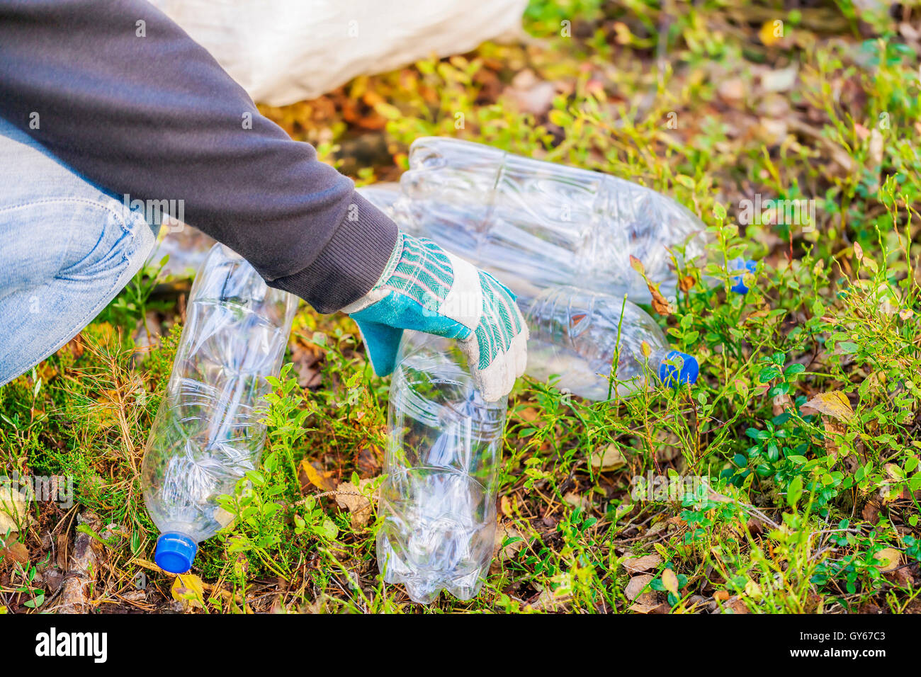 Man with bag picking up used plastic bottles Stock Photo - Alamy