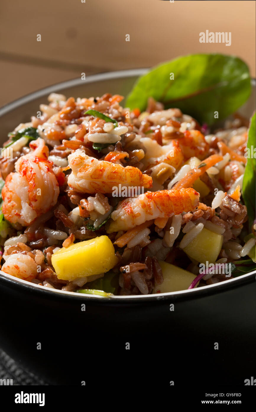 A black bowl of crayfish & mango salad with rice, crayfish, mango, red ...
