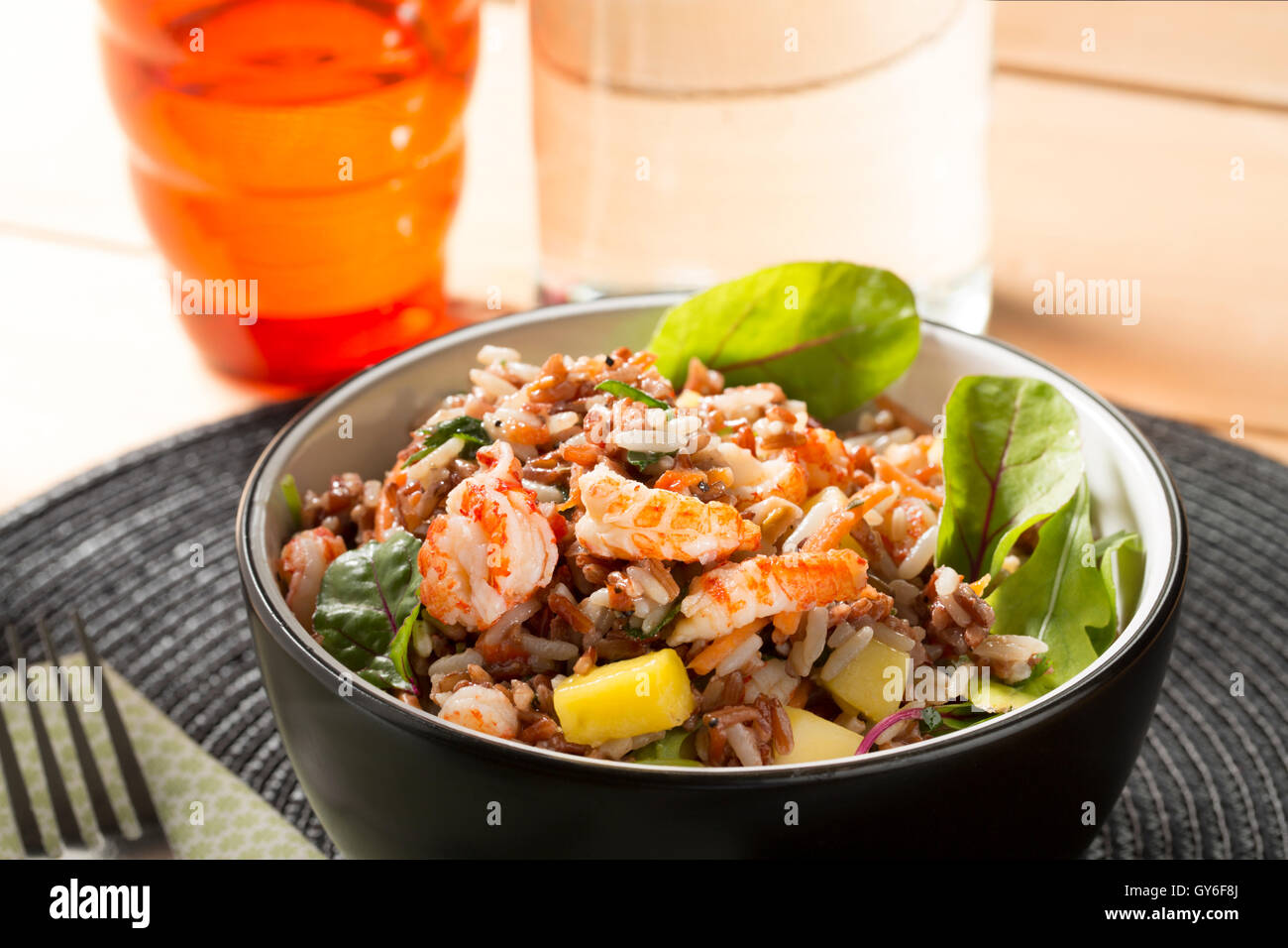 A black bowl of crayfish & mango salad with rice, crayfish, mango, red ...