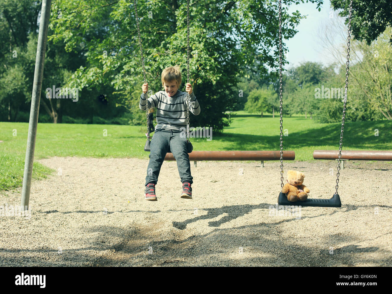 Cute autistic child sitting on the swing in the park Stock Photo - Alamy