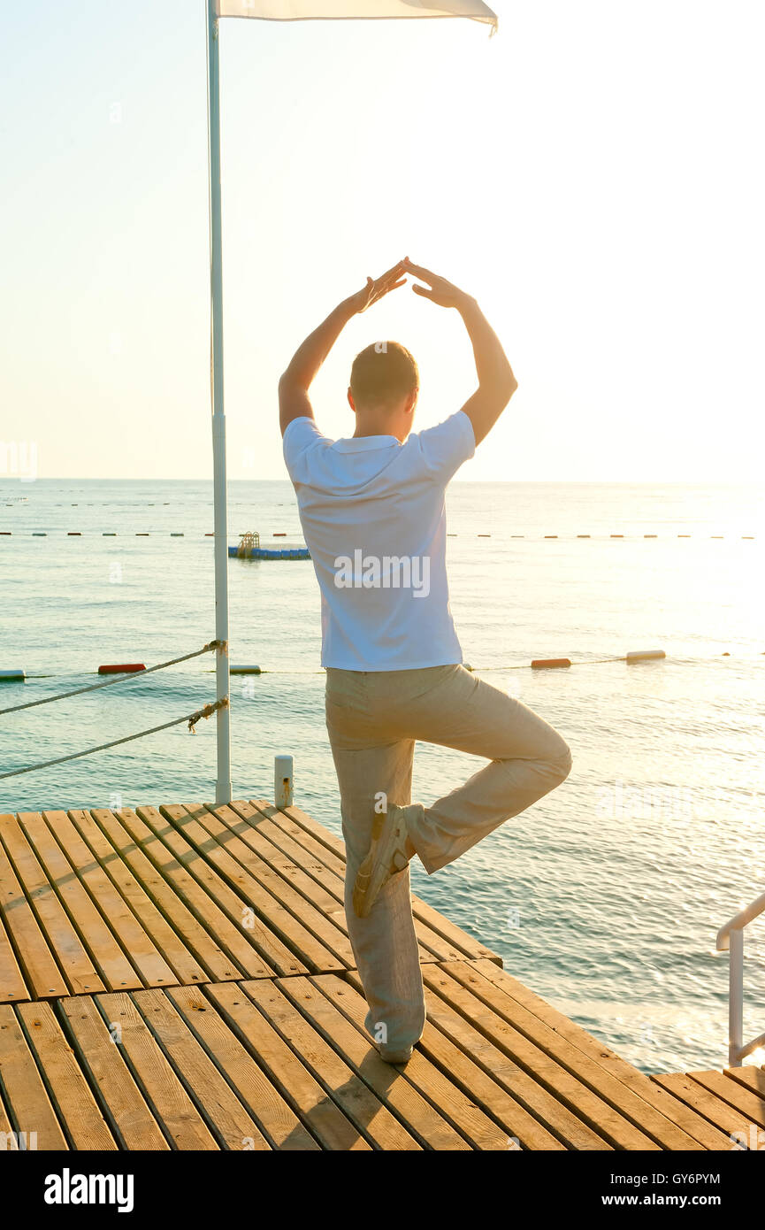 man standing on a pier on one leg and holds the balance Stock Photo - Alamy