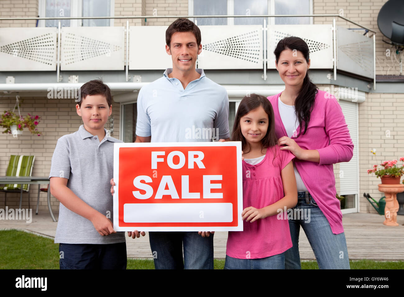 Family selling their home holding for sale sign Stock Photo - Alamy
