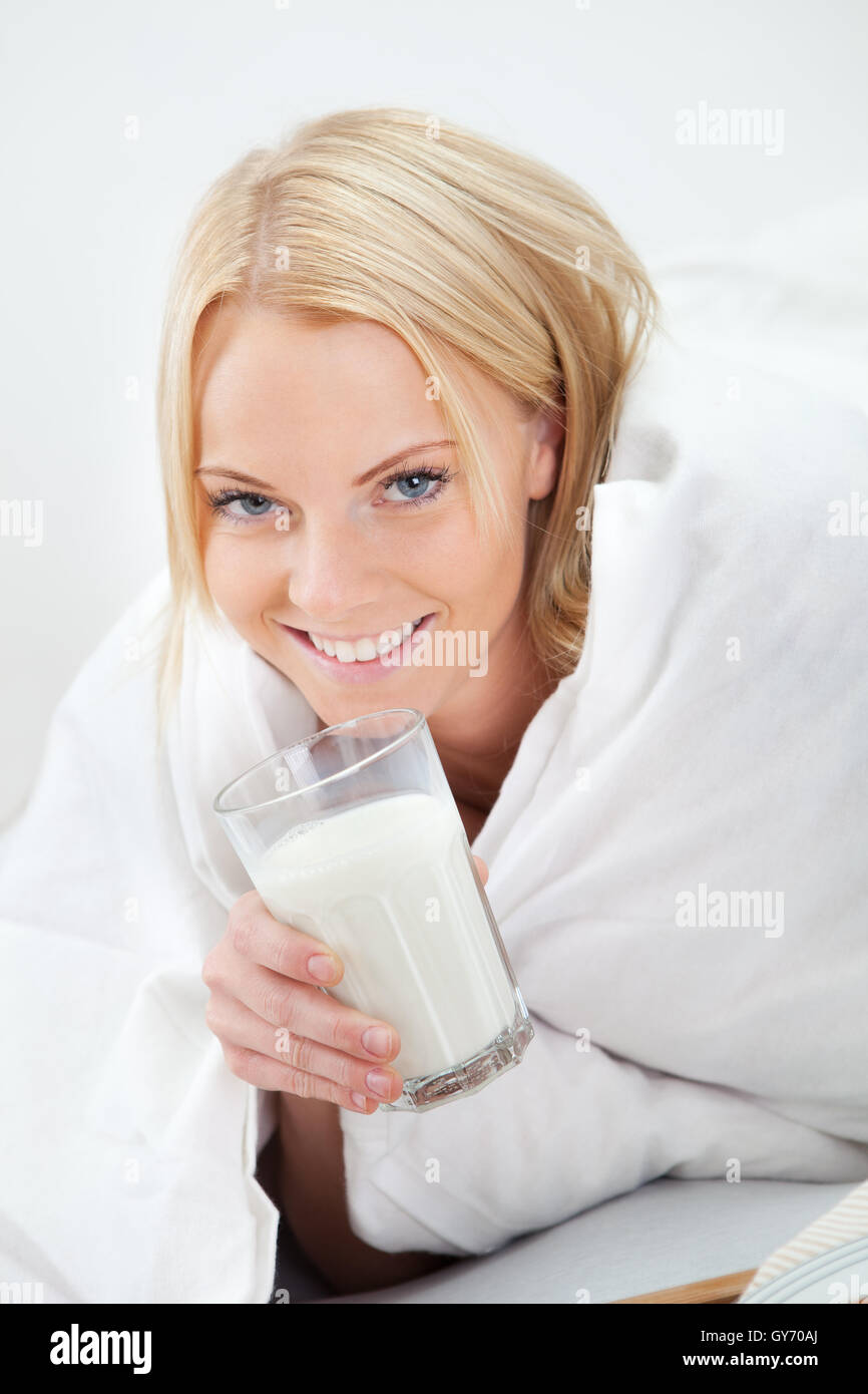 Beautiful woman drinking milk in bed Stock Photo - Alamy