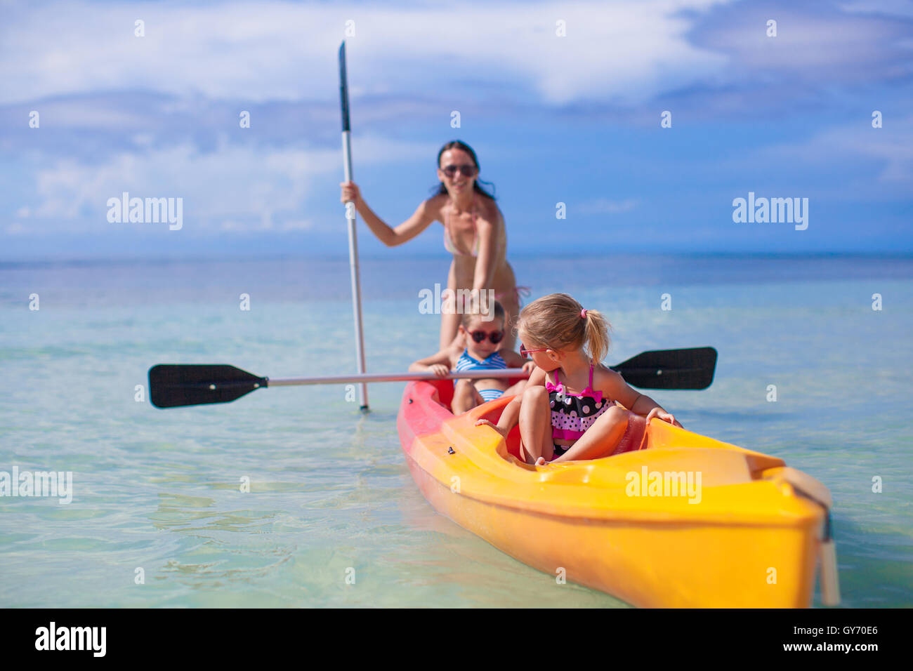 Two little girl and beautiful mother kayaking at tropical warm sea ...