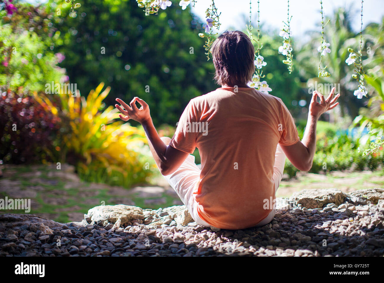 Young man sitting in the lotus position at beautiful resort Stock Photo ...
