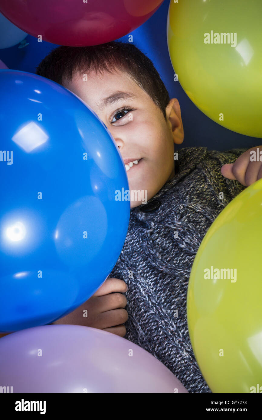 Sweet, child surrounded by balloons at a party Stock Photo - Alamy