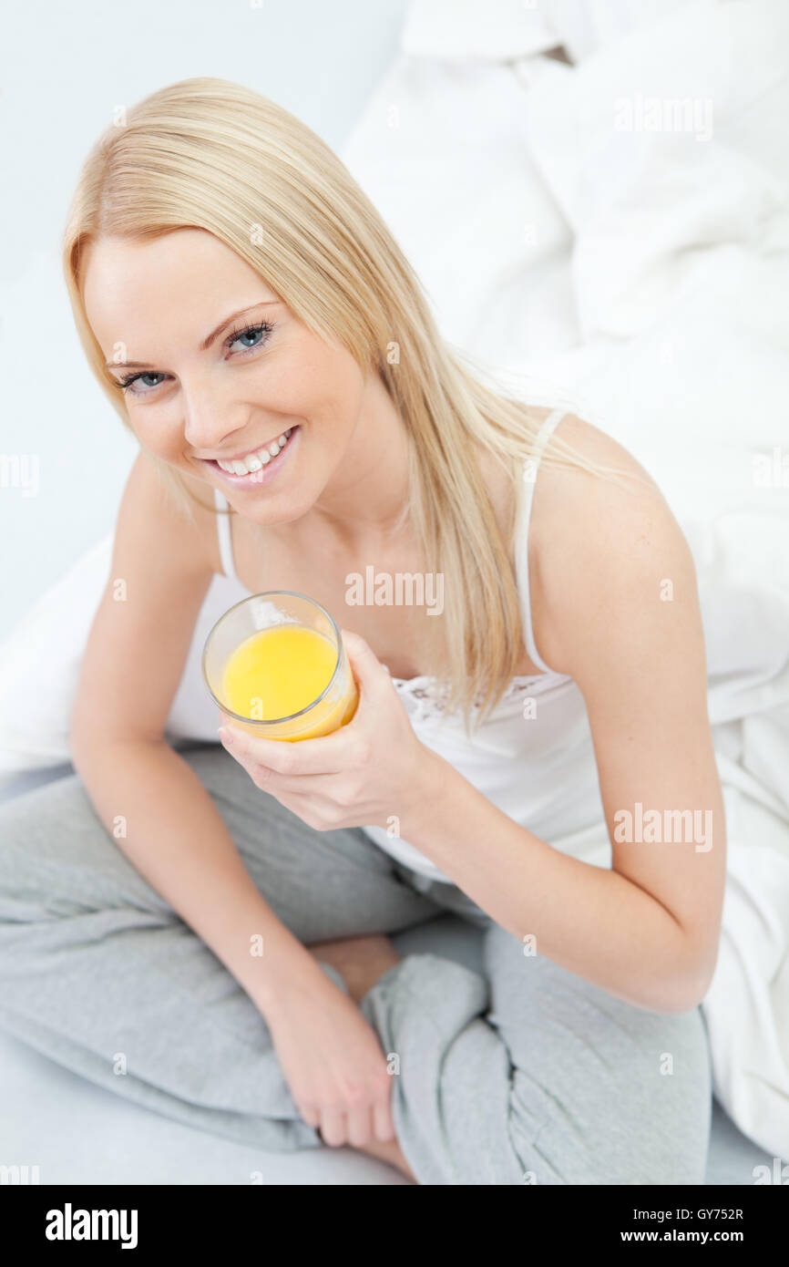 Beautiful woman drinking juice in bed Stock Photo - Alamy