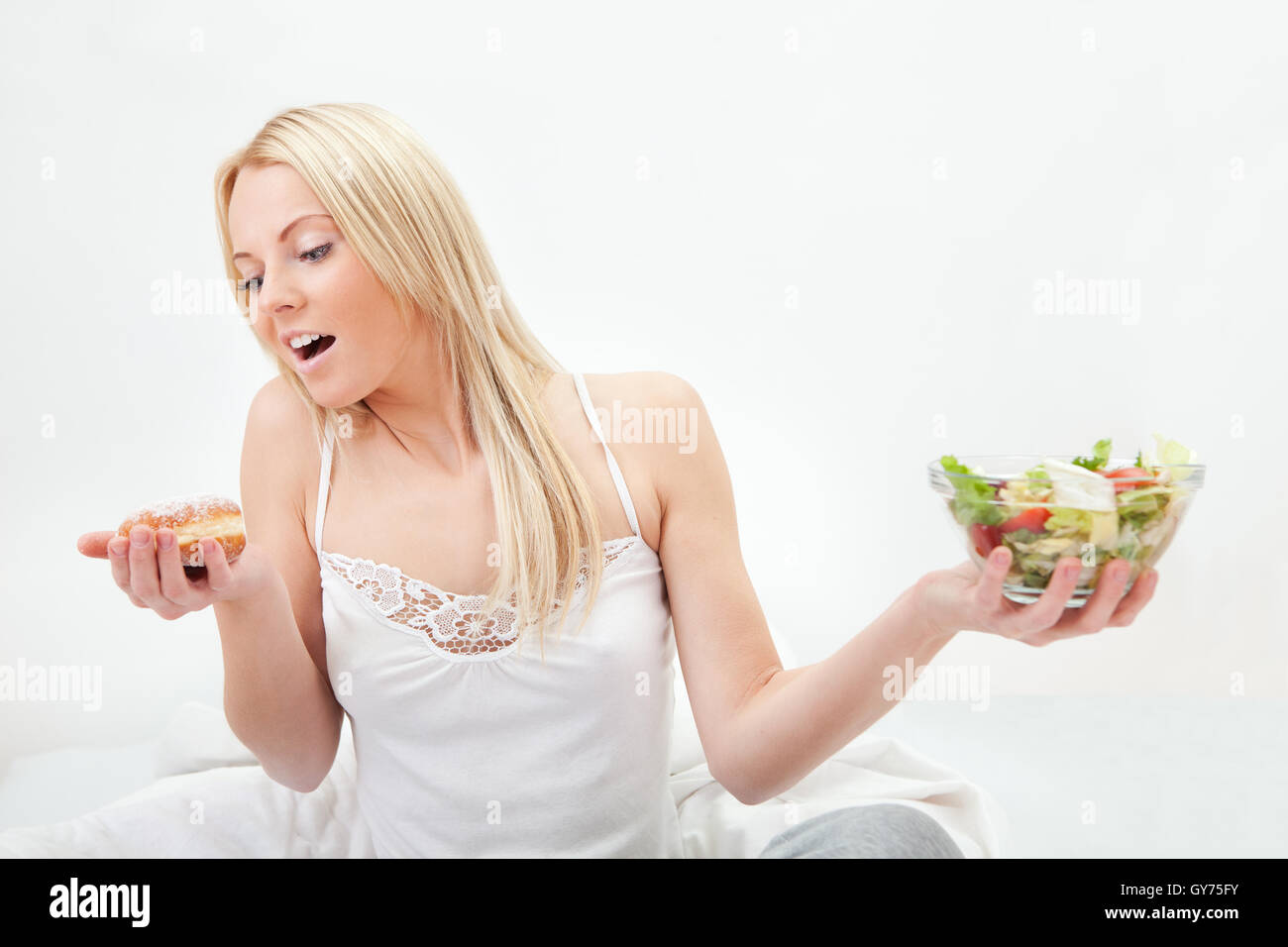 Tempted young woman making a food choice Stock Photo - Alamy
