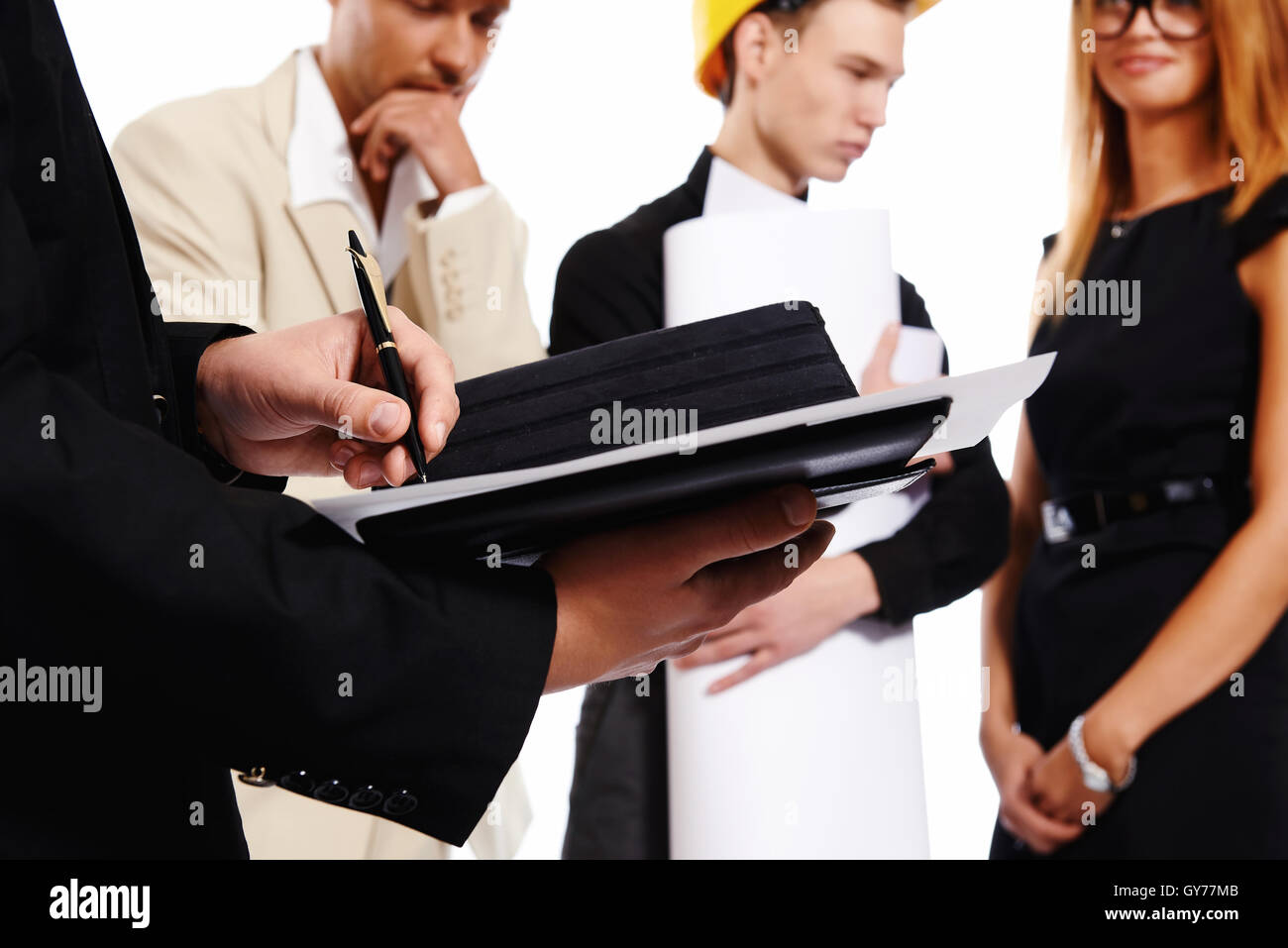 Construction team at business meeting signing a document. Studio shot ...