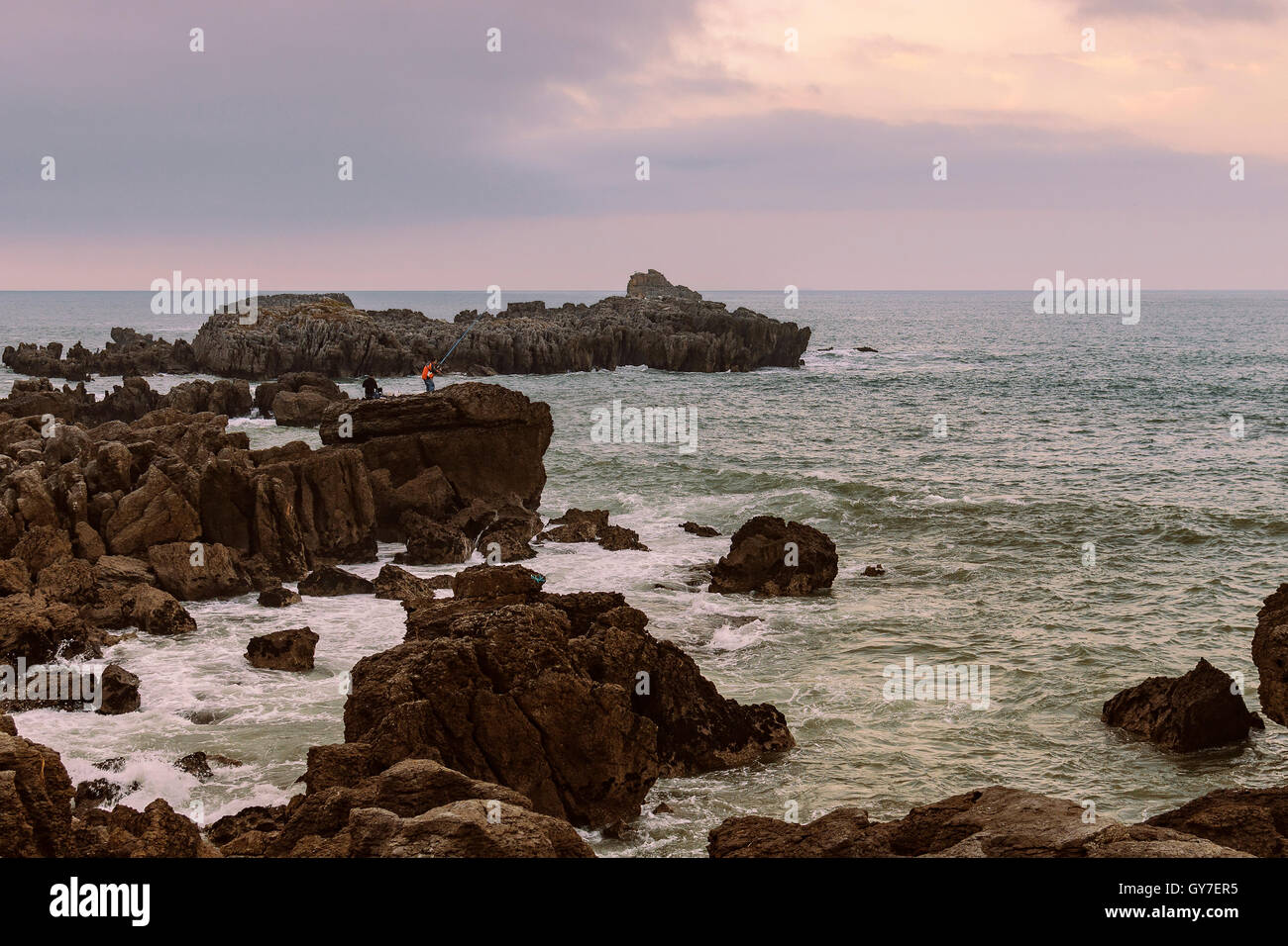 Two fishermen with their rods on the rocks, sea bottom, coastal in ...