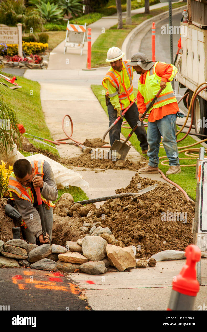 Construction workers install internet cable conduits on a residential ...