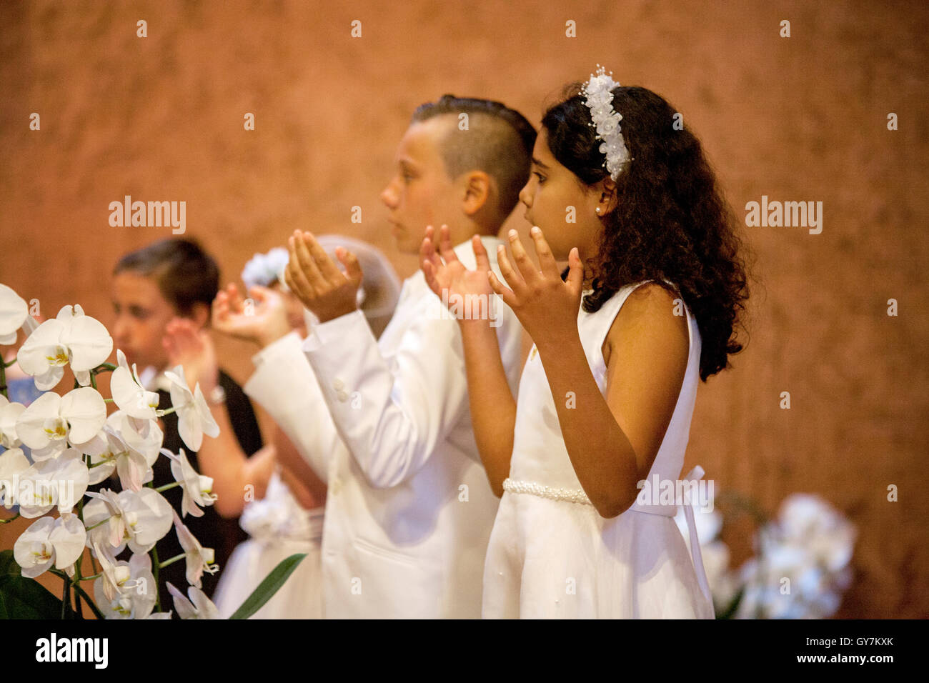 Formally dressed Hispanic and Caucasian children sing a hymn during ...