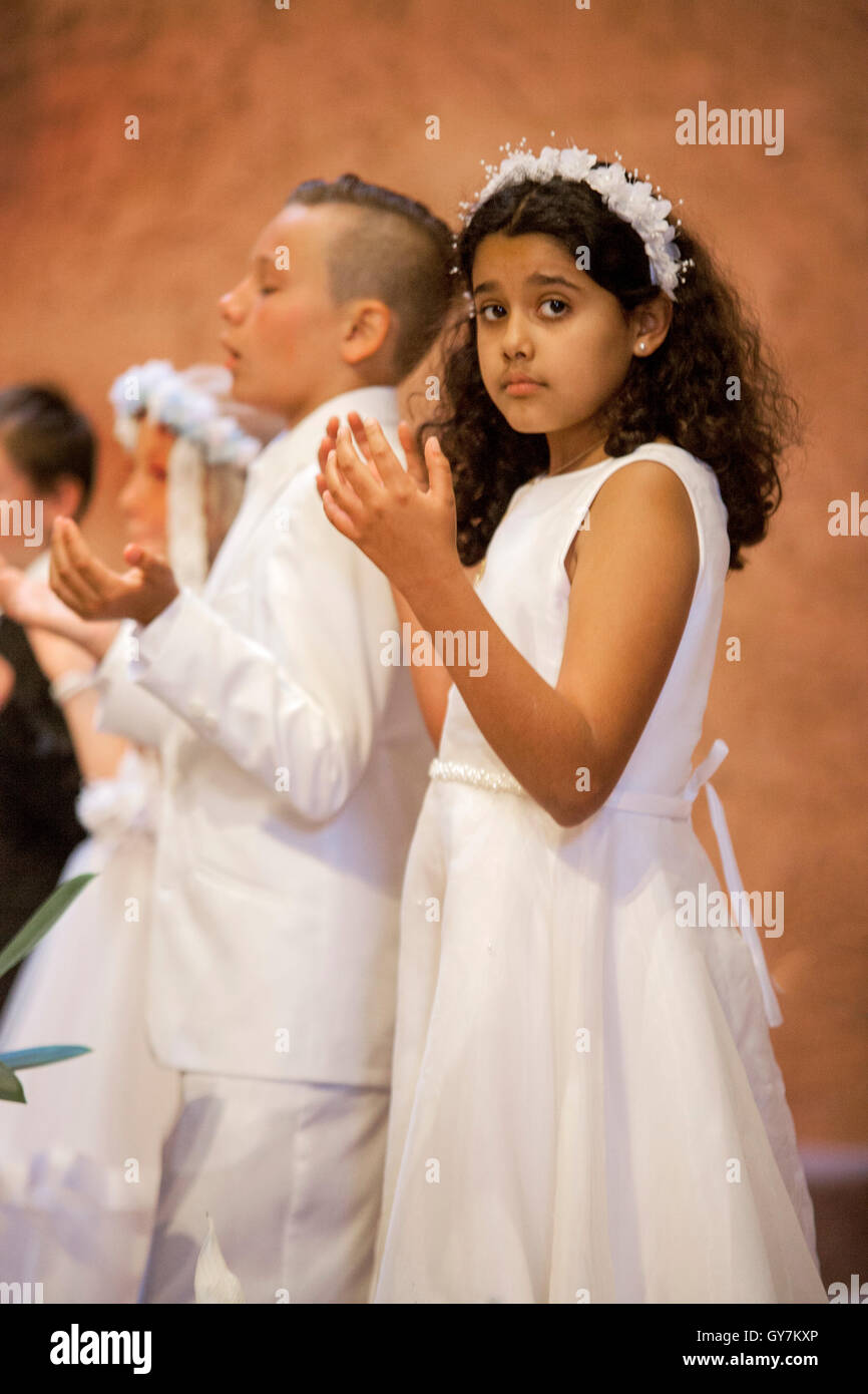 Formally dressed Hispanic and Caucasian children sing a hymn during ...