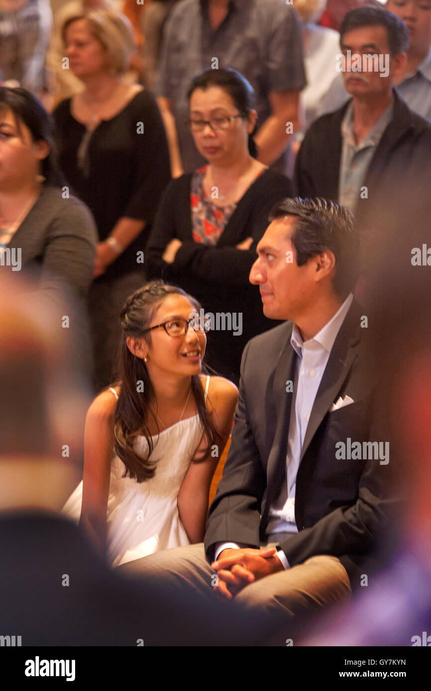 A formally dressed Hispanic girl and her father attend First Communion ...