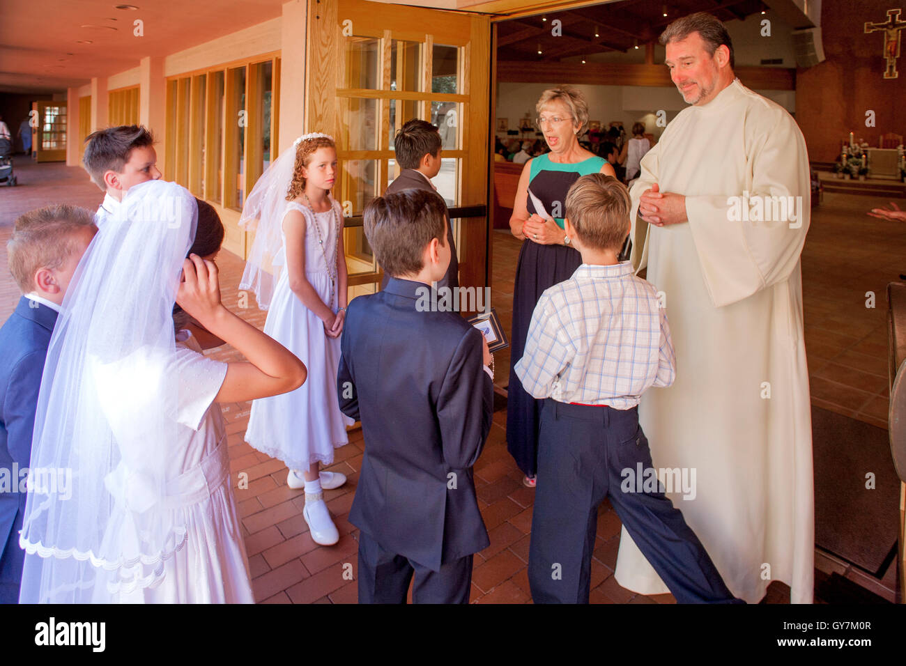 Formally dressed Hispanic and Caucasian socialize with a deacon before ...