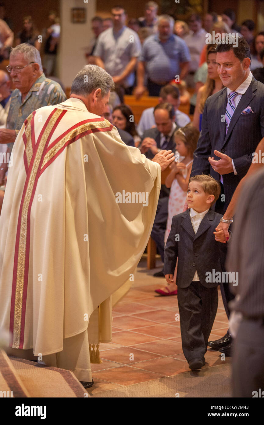 A formally dressed boy receives a blessing at First Communion mass at a ...