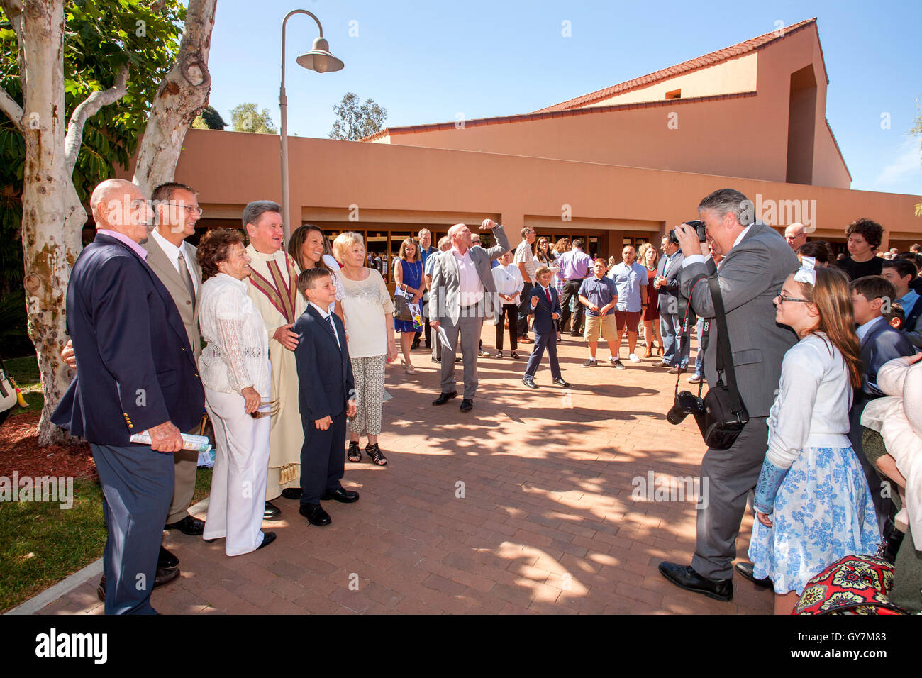 A robed monsignor poses for photos with formally dressed multiracial ...