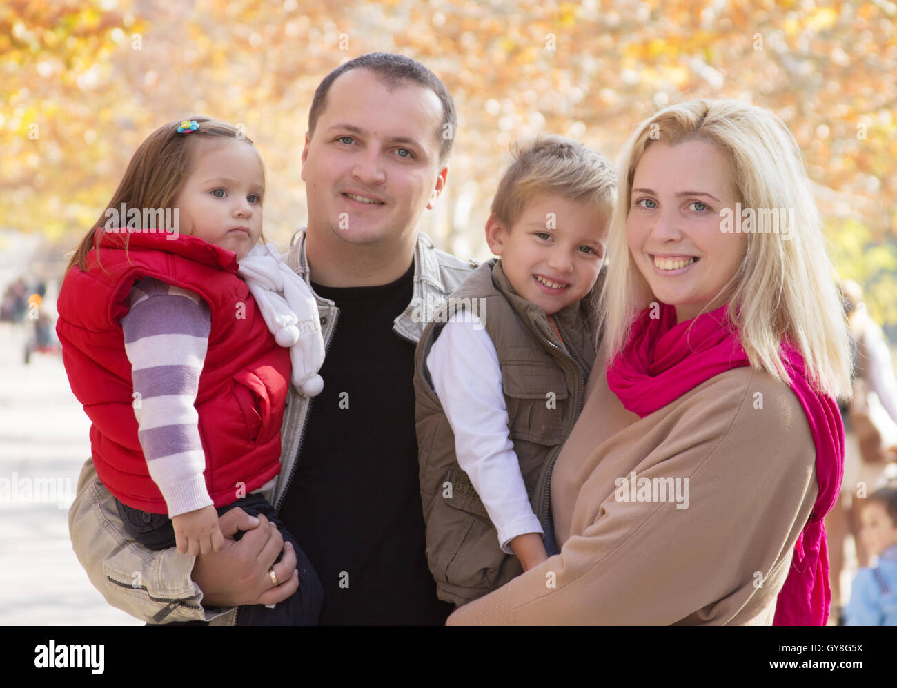 Family with two children in autumn park Stock Photo - Alamy