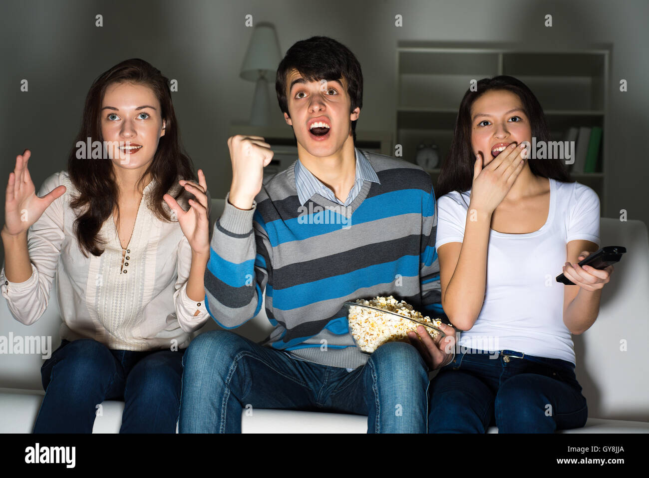 group of young people watching TV on the couch Stock Photo - Alamy