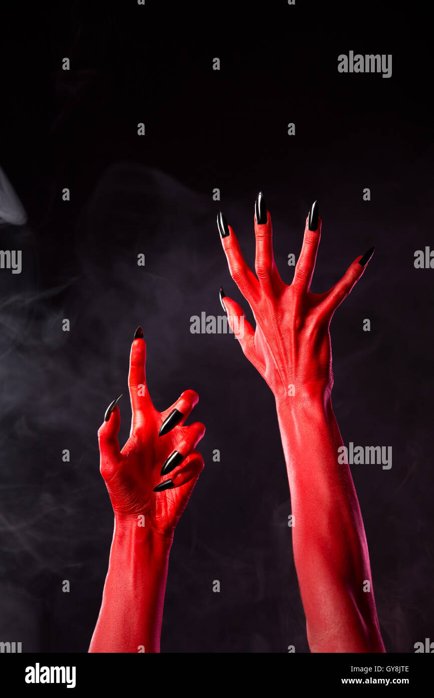 Spooky red devil hands with black nails Stock Photo - Alamy