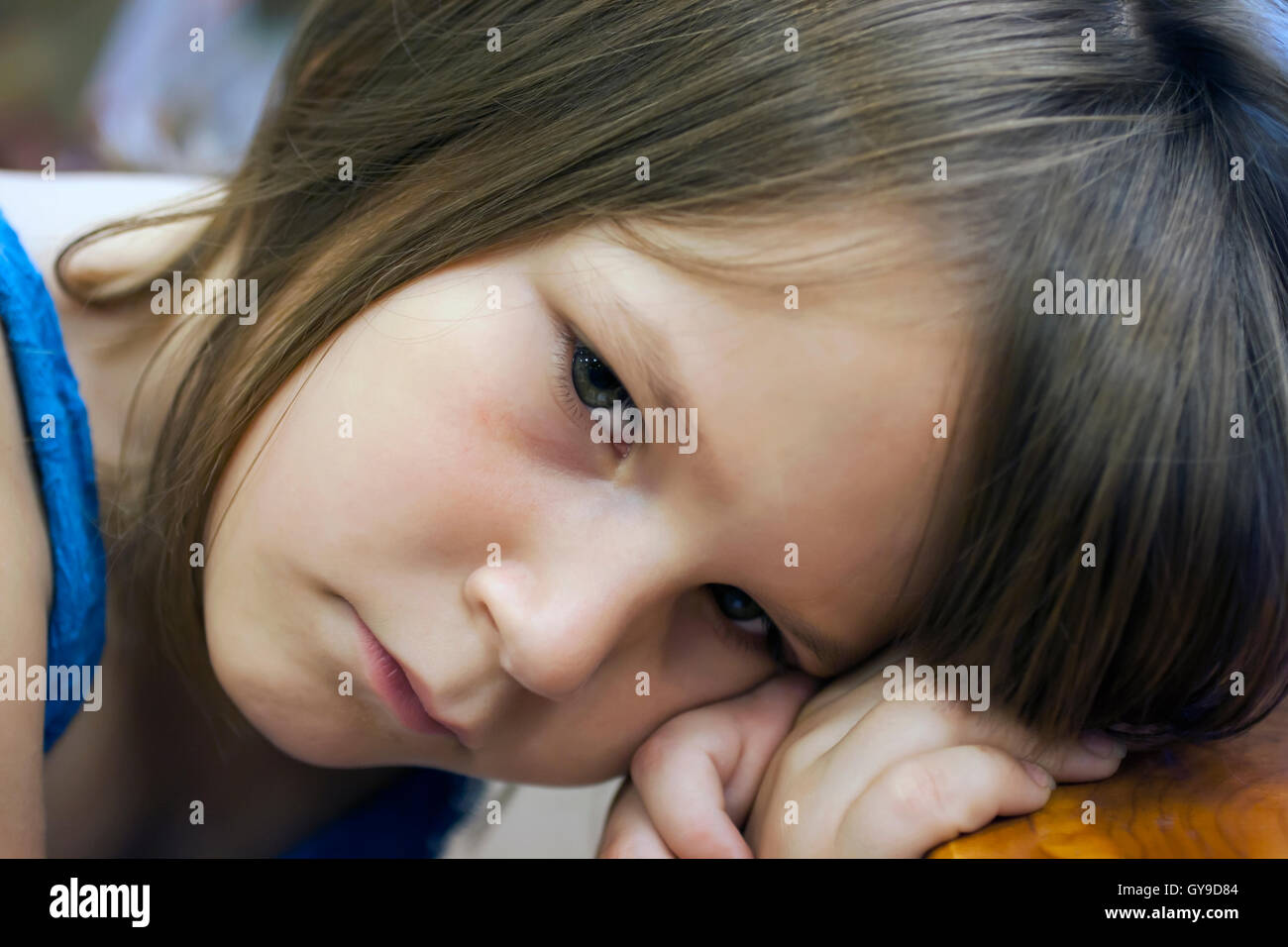 Sad girl resting her head on a table Stock Photo - Alamy