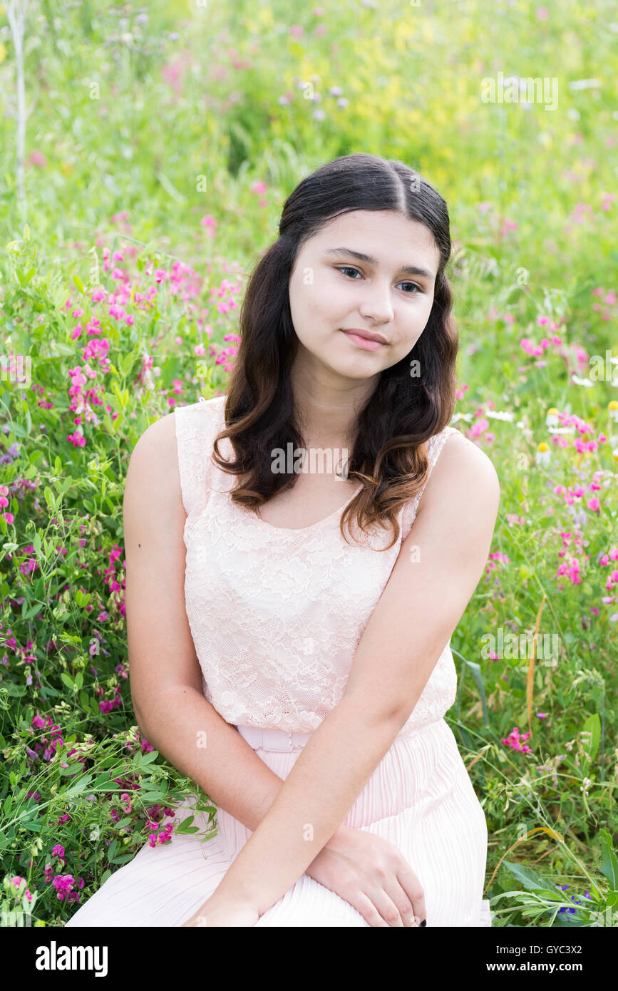 Pretty girl sits on richly meadow Stock Photo - Alamy