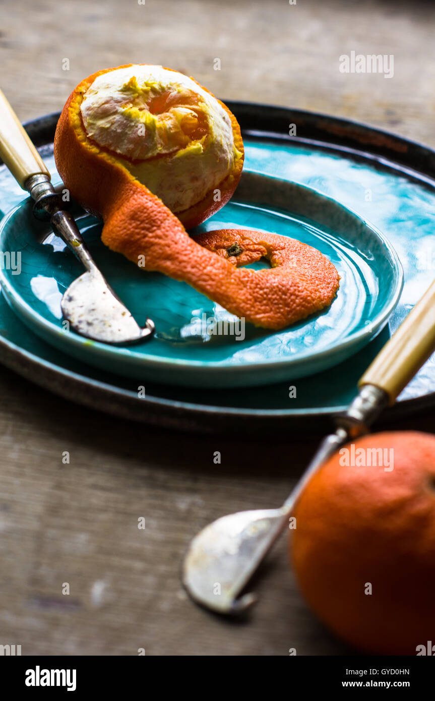 Sliced and whole orange fruit on bright turquoise ceramic plates over ...