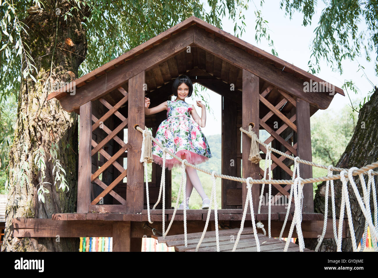 beautiful little girl in a dress stands in the tree house at the ...