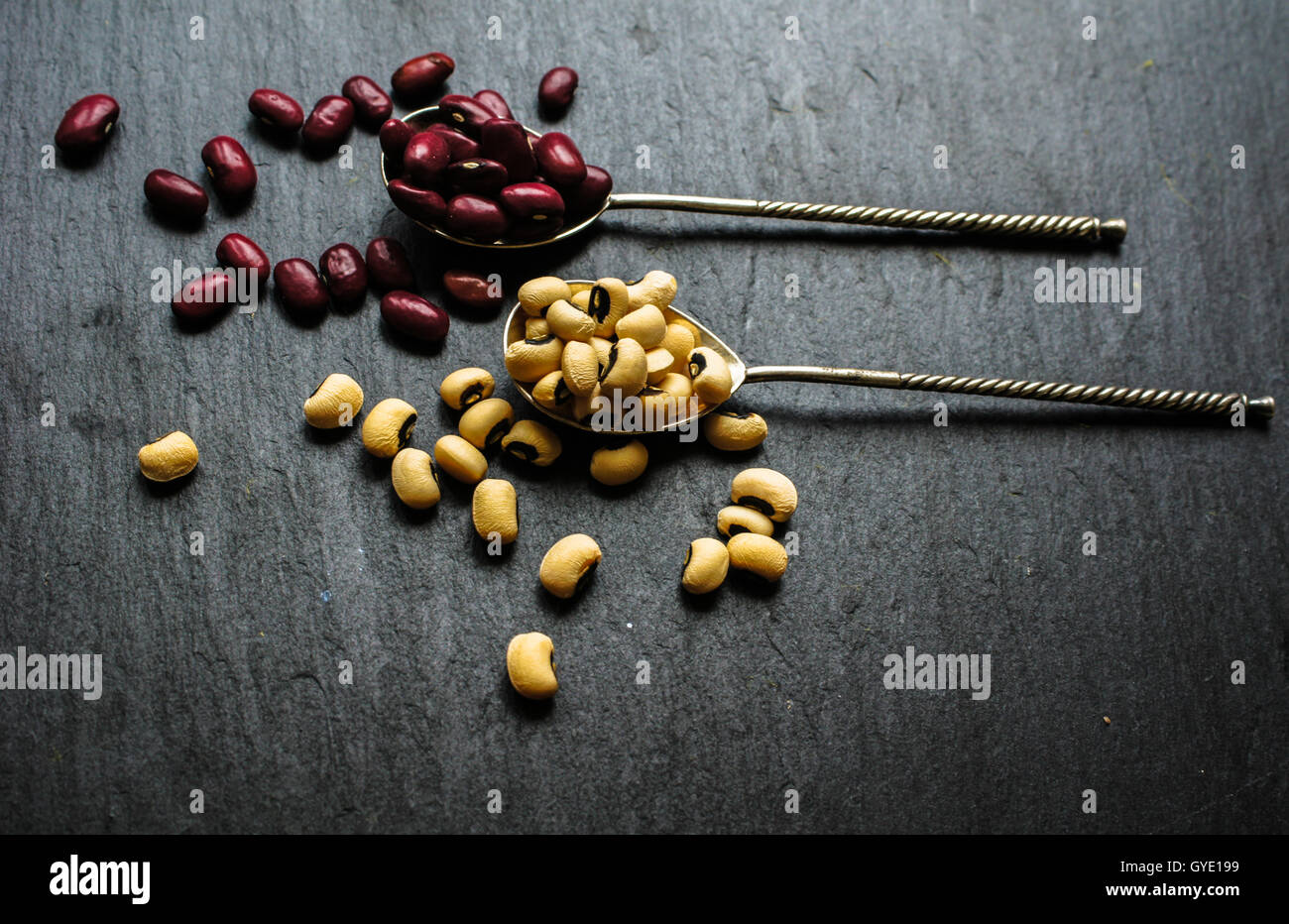 Different types of beans in the vintage spoons on the black stone ...