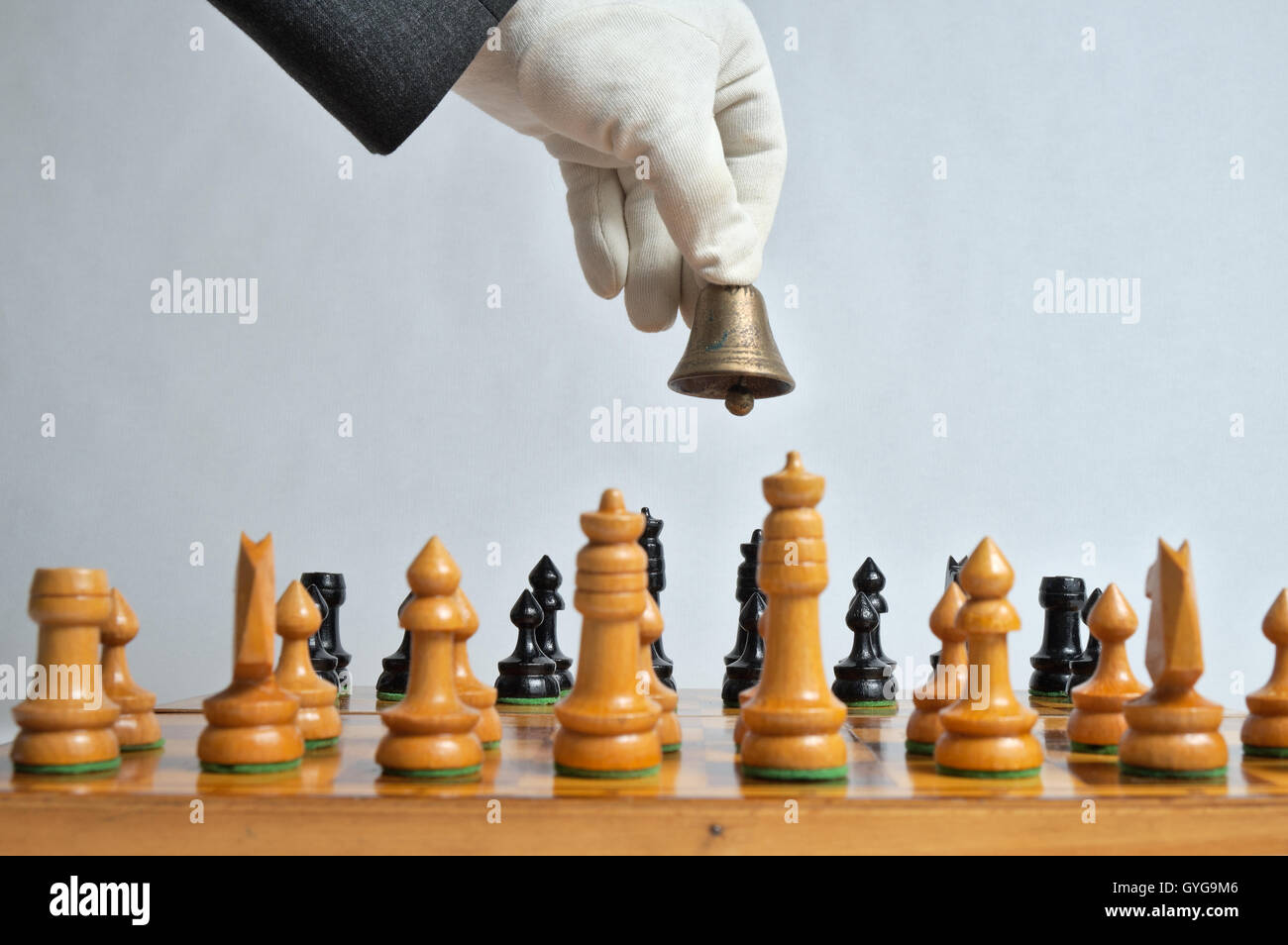White glove ringing a bell over a chessboard. Games and luxury themes ...