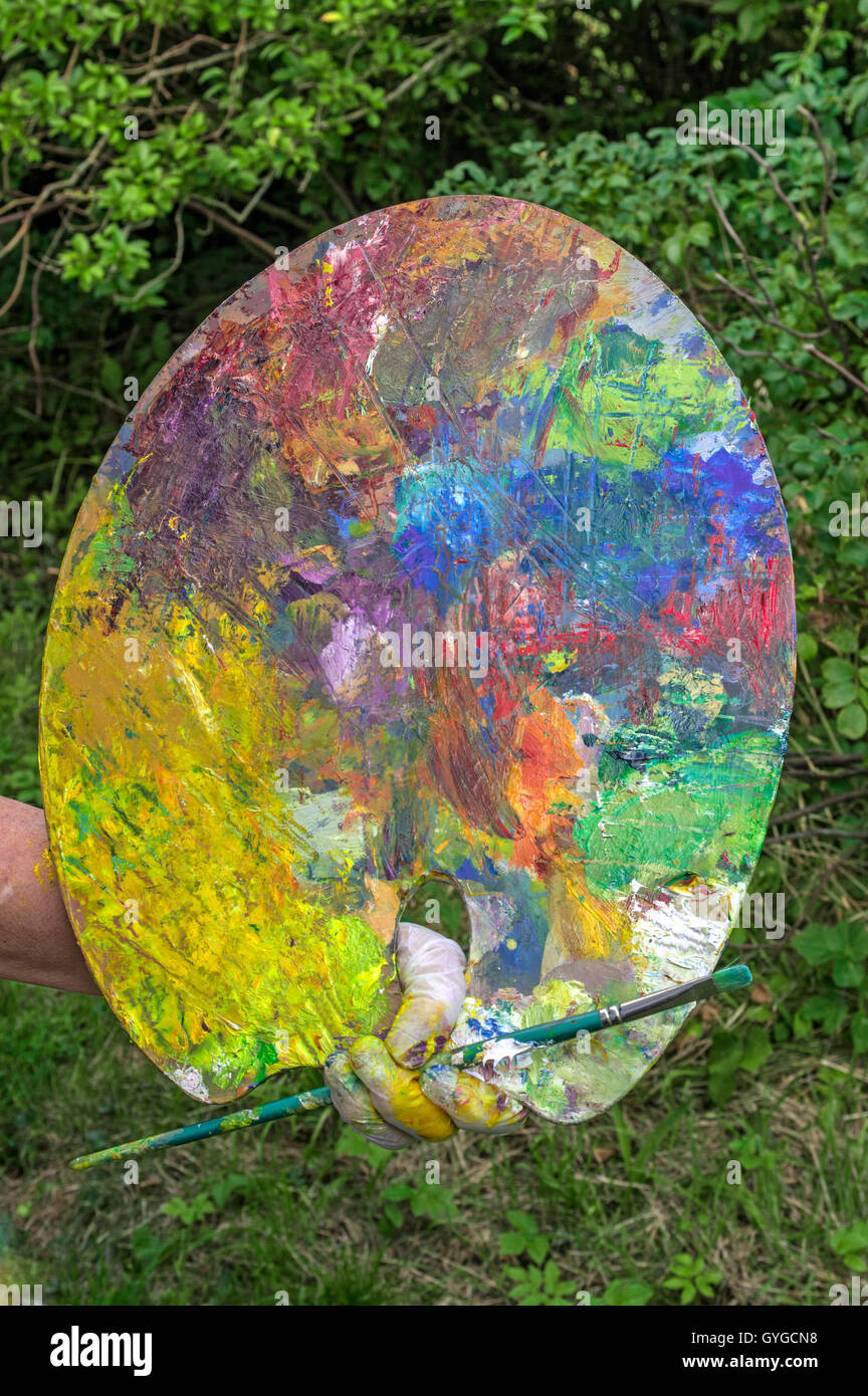 An artist painting a landscape, having scraped off colours ready to ...