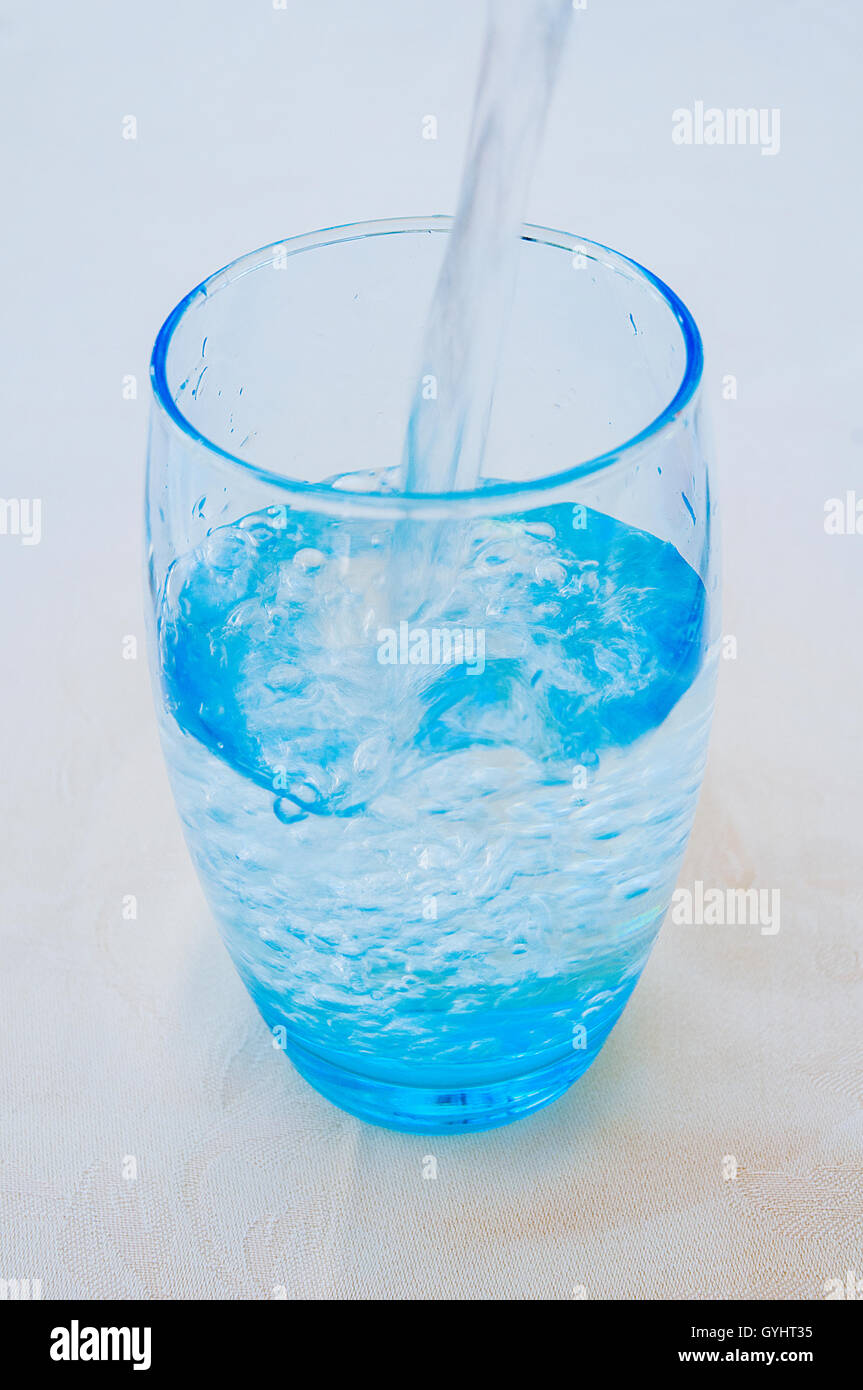 Pouring water in a blue glass Stock Photo - Alamy