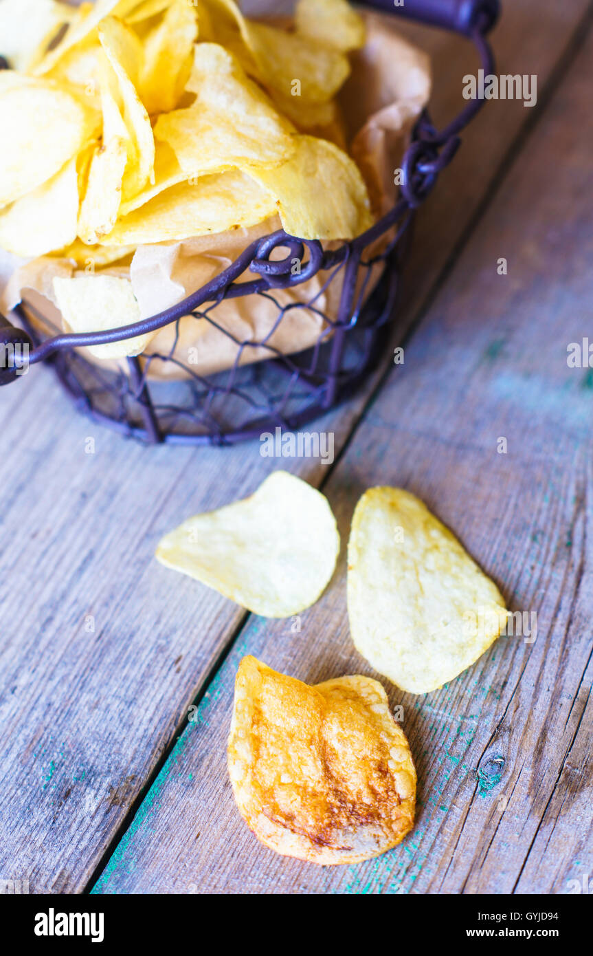 Crispy potato chips in rustic pot on old wooden table. Selective focus ...